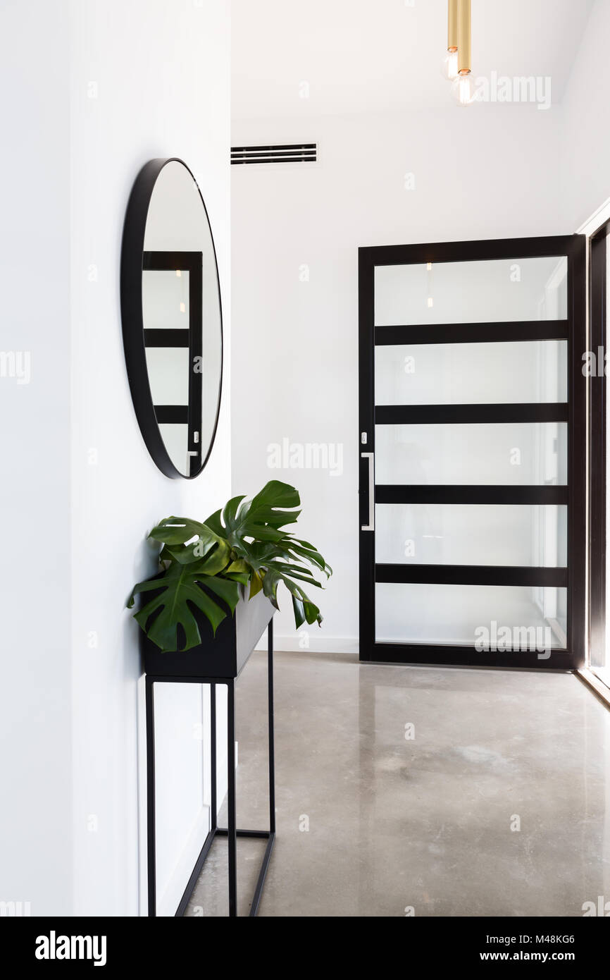Glass entry door to foyer with planter and round mirror Stock Photo - Alamy