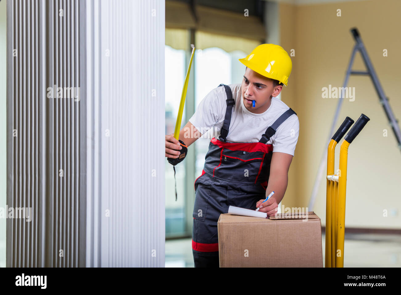 Delivery man taking dimensions with tape measure Stock Photo - Alamy