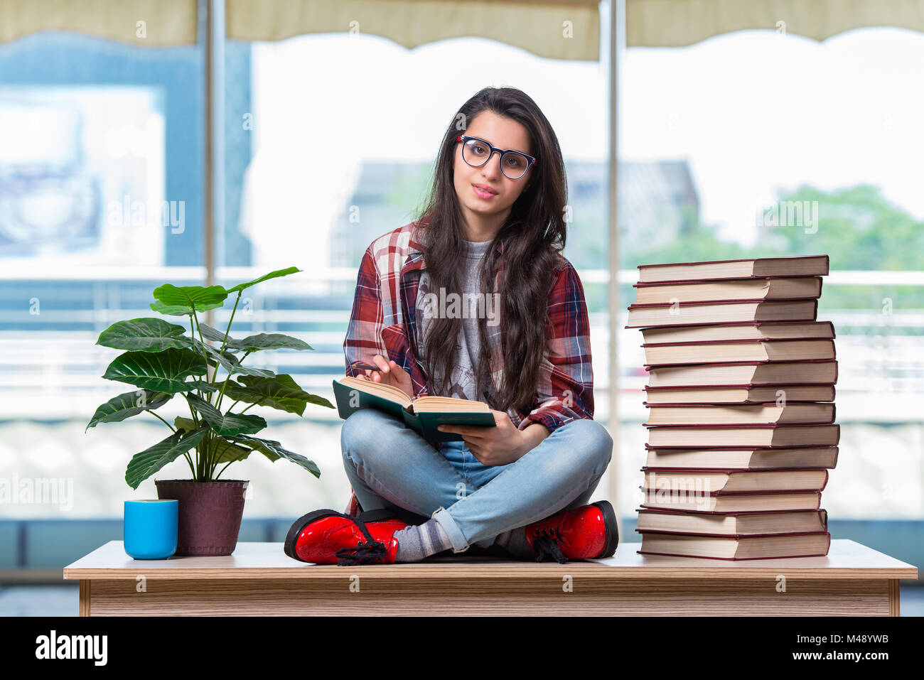 Student sitting on the desk with books Stock Photo - Alamy