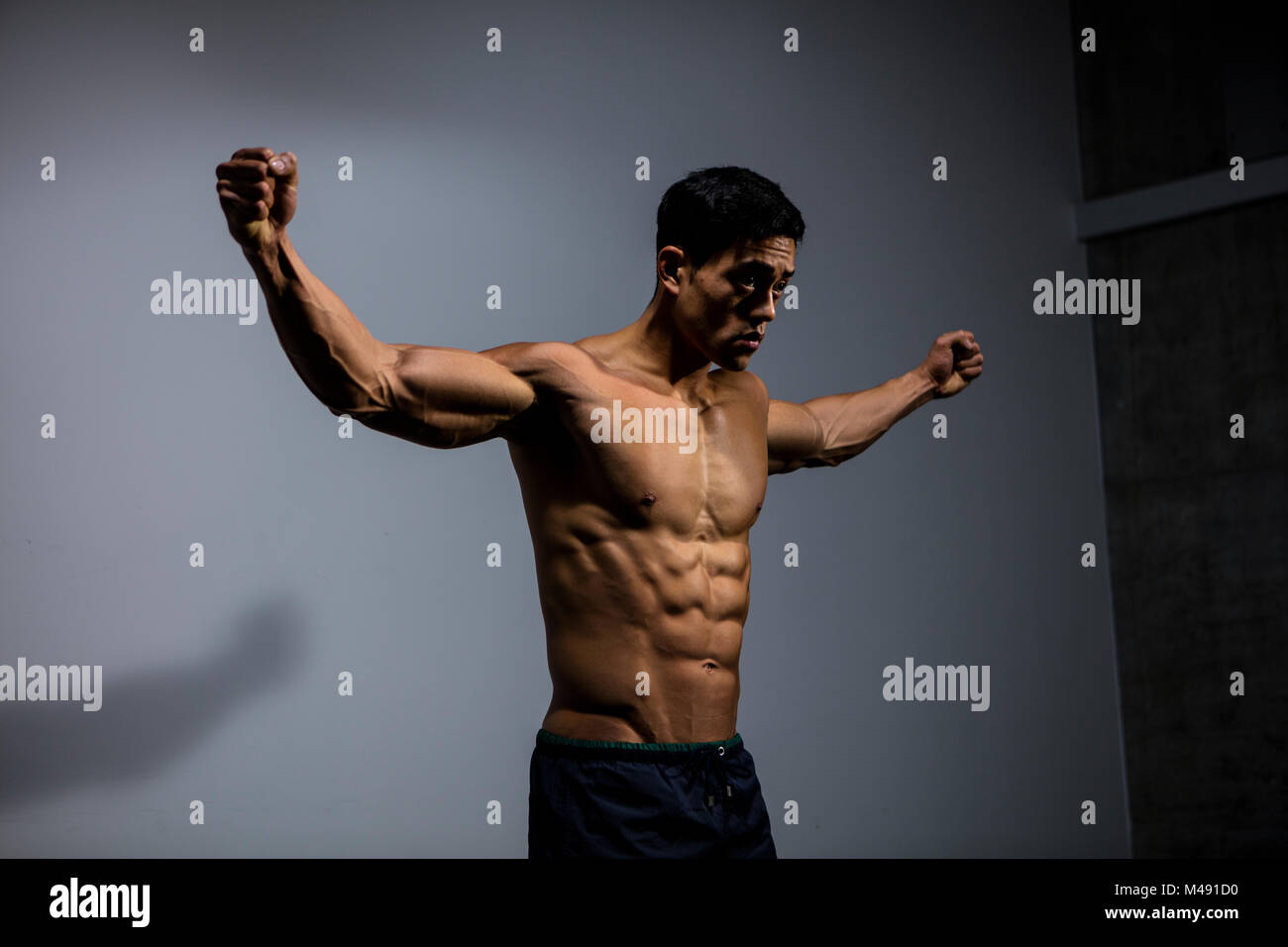 Asian fitness model flexing his muscular torso. Medium shot. Angled ...
