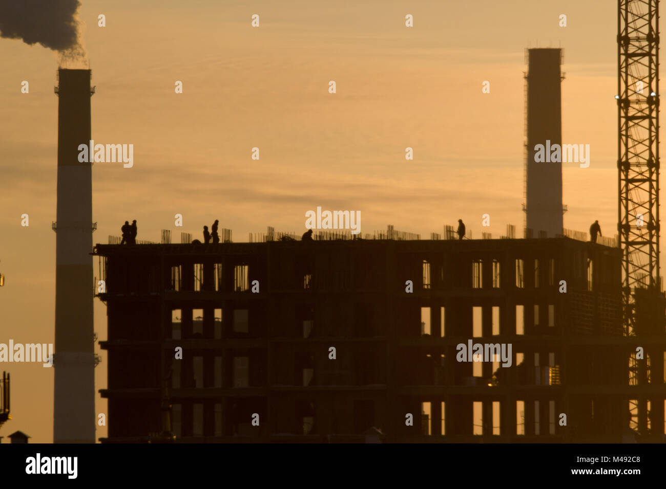 Construction side - silhouette at sunset - workers, cranes - unfinished ...