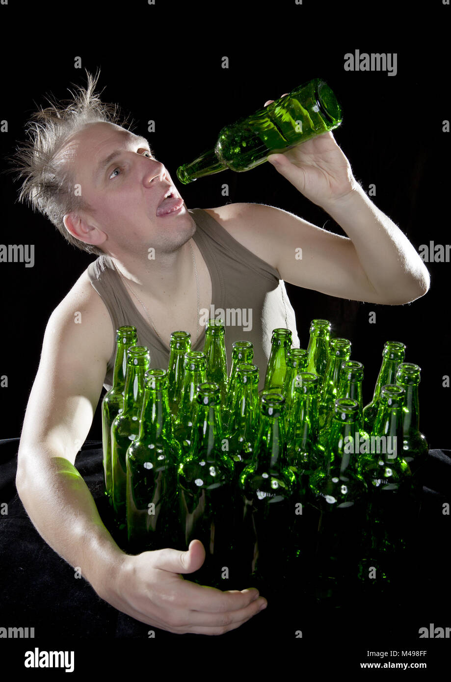The tipsy man sits with a heap of beer bottles Stock Photo - Alamy