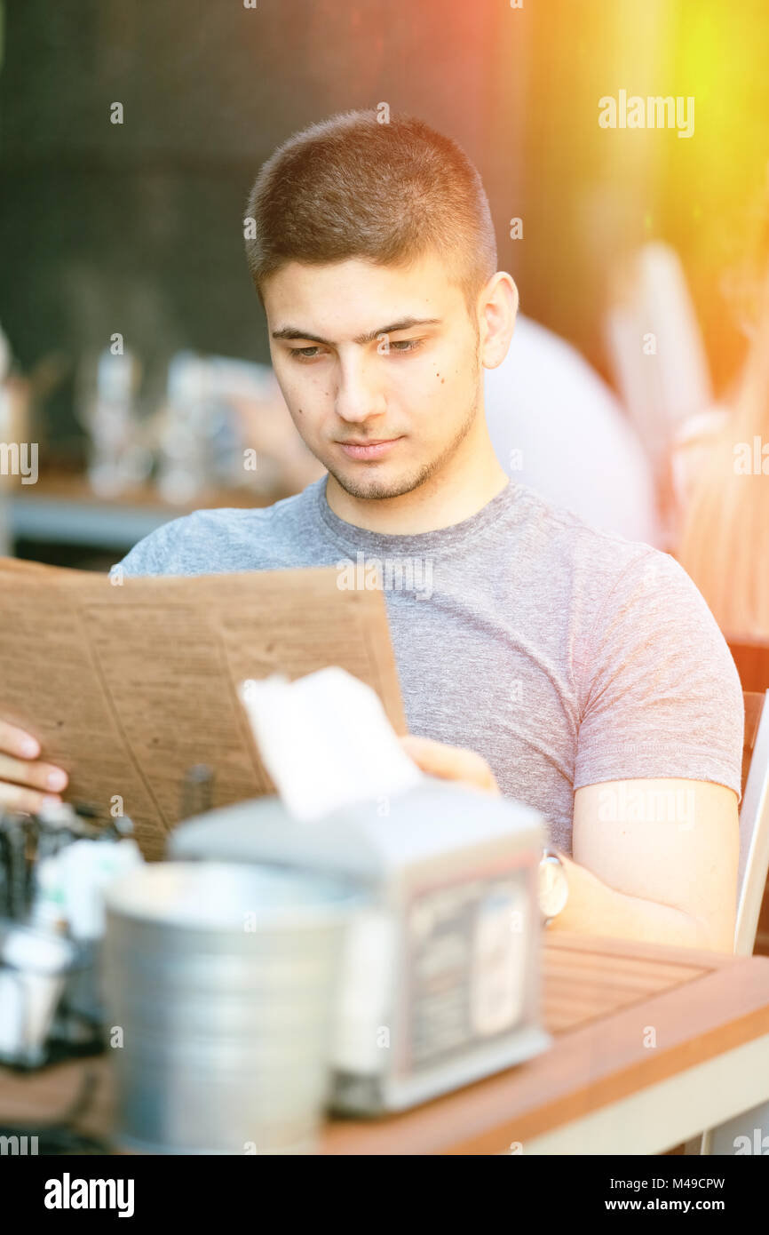 Man in outdoor restaurant looking at the menu Stock Photo - Alamy