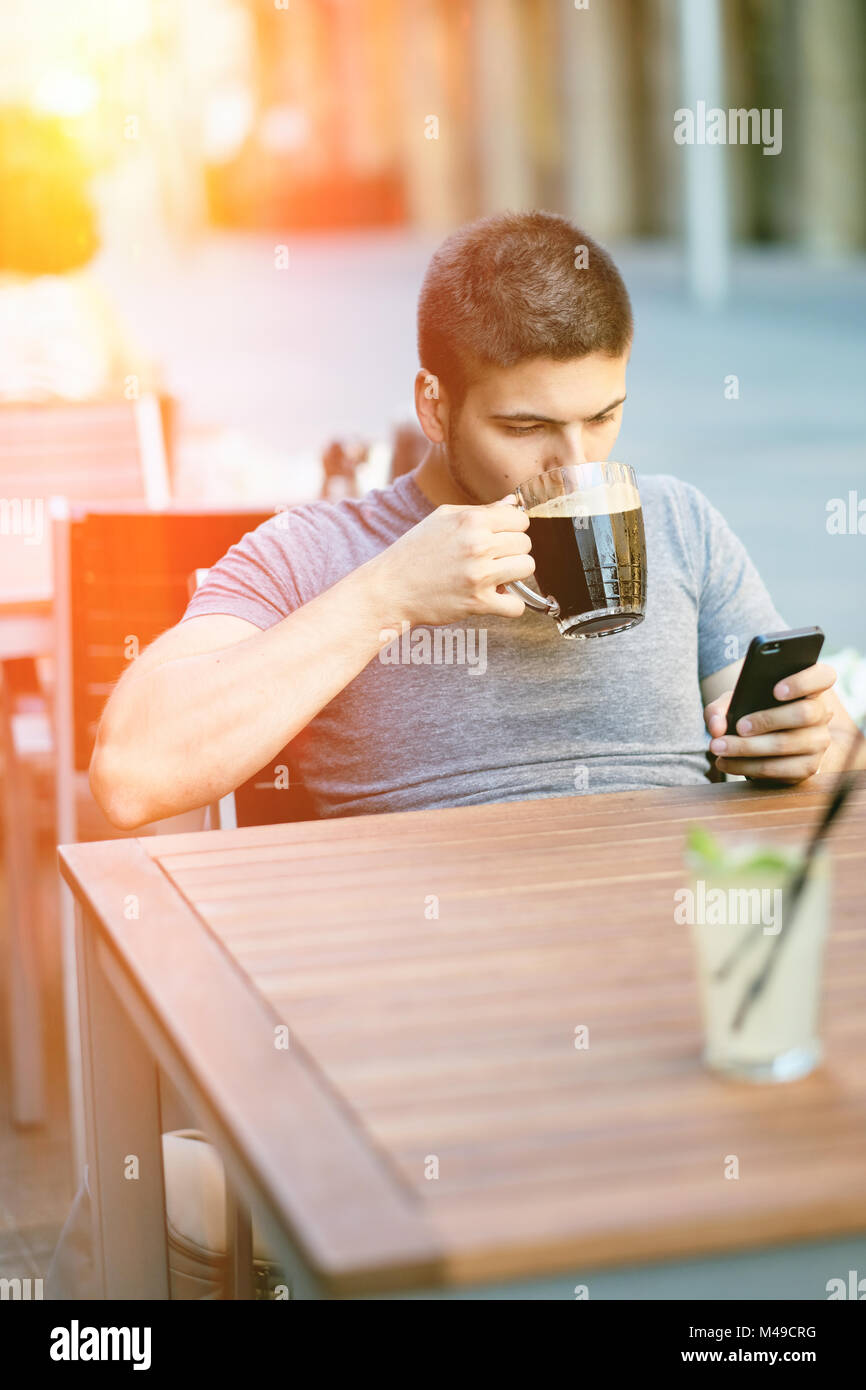 Man with mobile phone drinking beer Stock Photo - Alamy