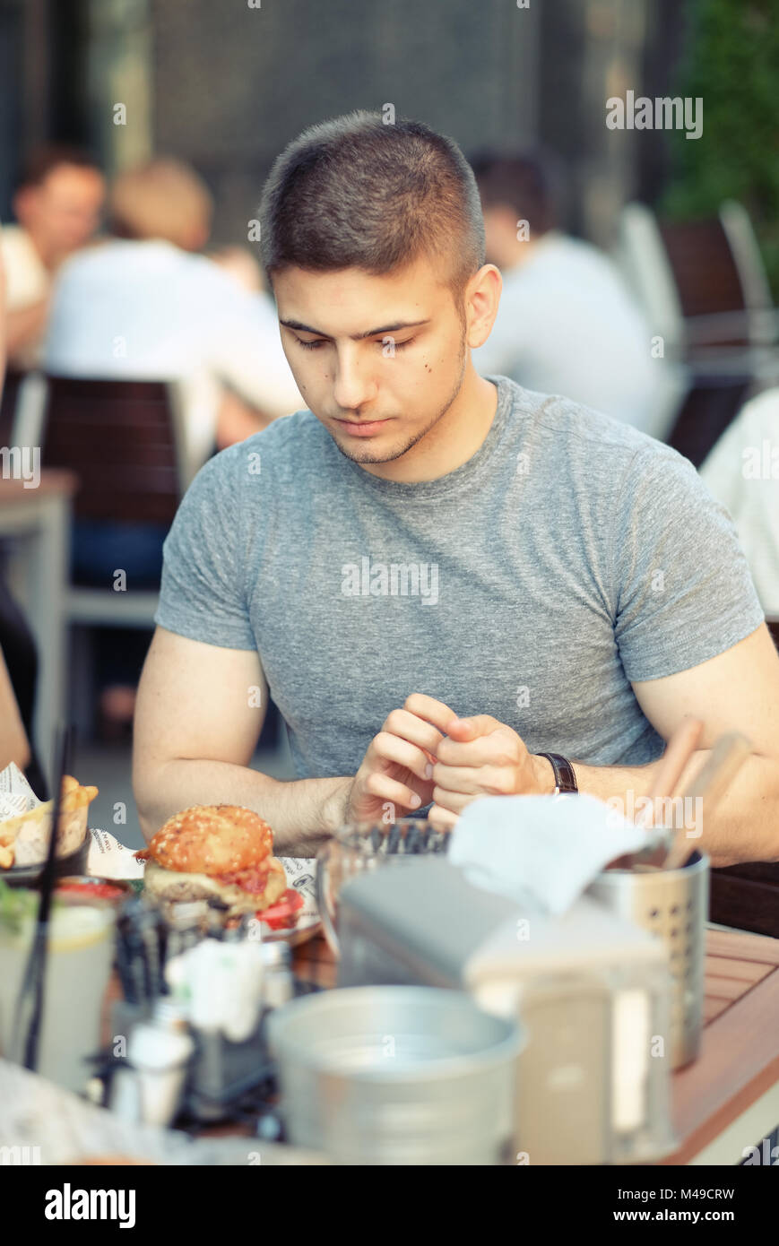 Man having cheeseburger in restaurant Stock Photo - Alamy