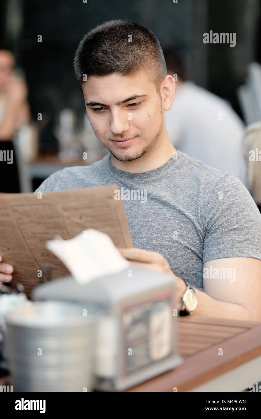 Man in outdoor restaurant looking at the menu Stock Photo - Alamy