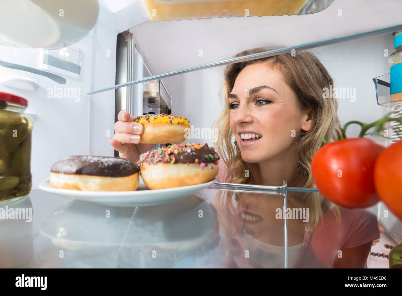 Young Happy Woman Taking Donut From Plate In Refrigerator Stock Photo ...
