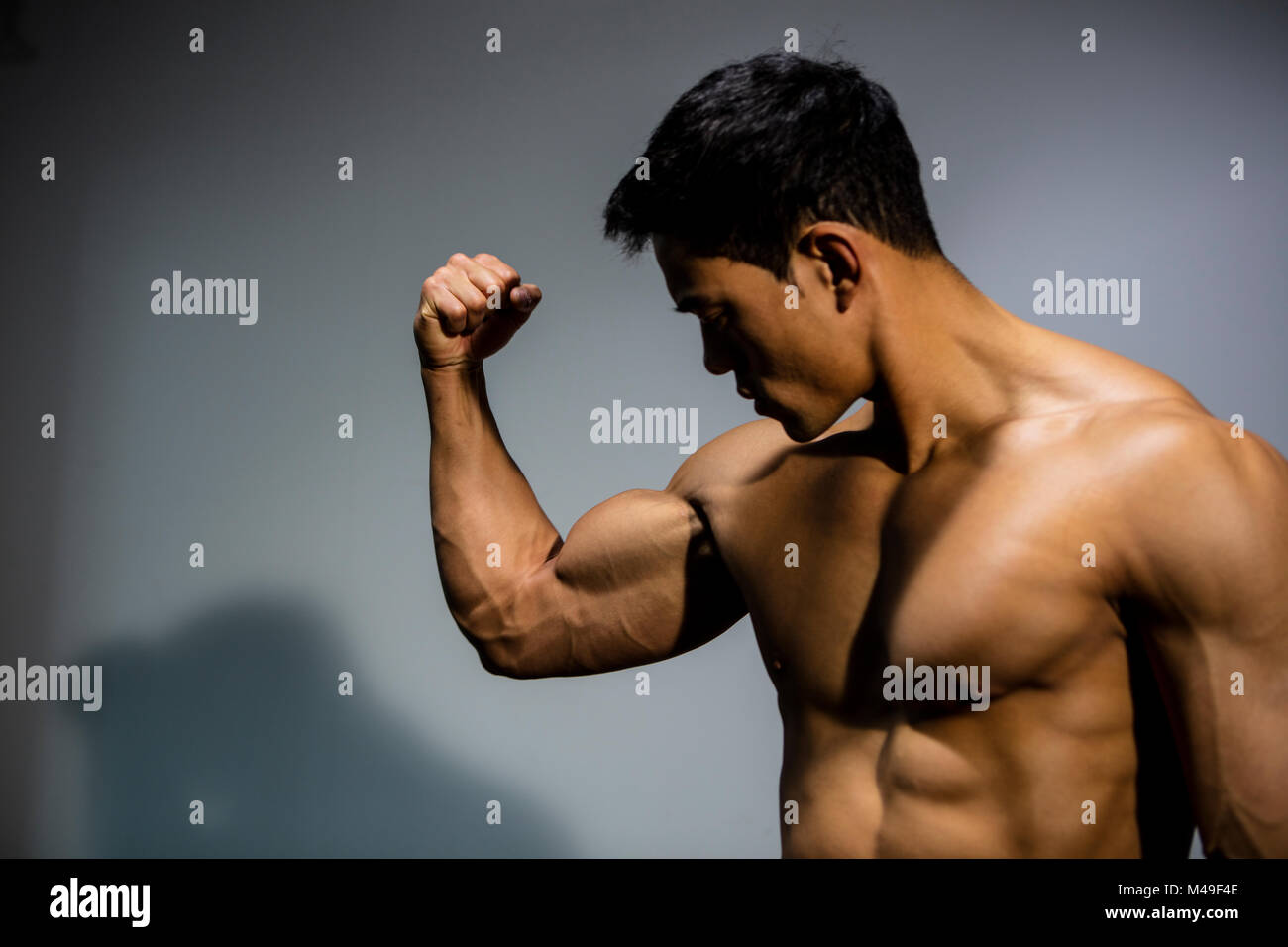 A fitness model flexes his bicep looking towards the muscle. Medium ...
