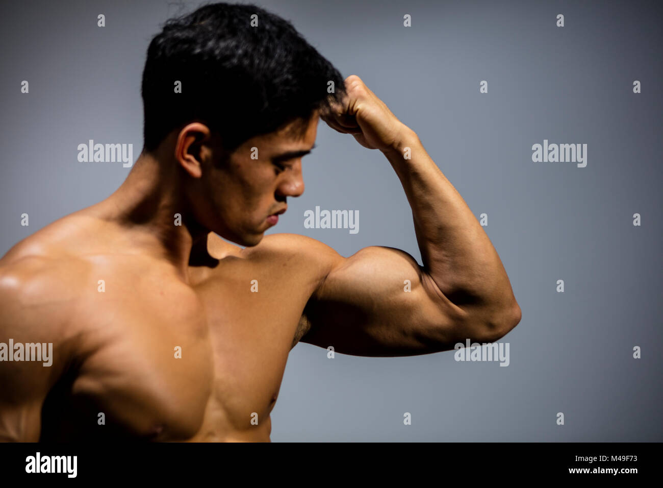 A fitness model flexes his bicep looking towards the muscle. Medium ...