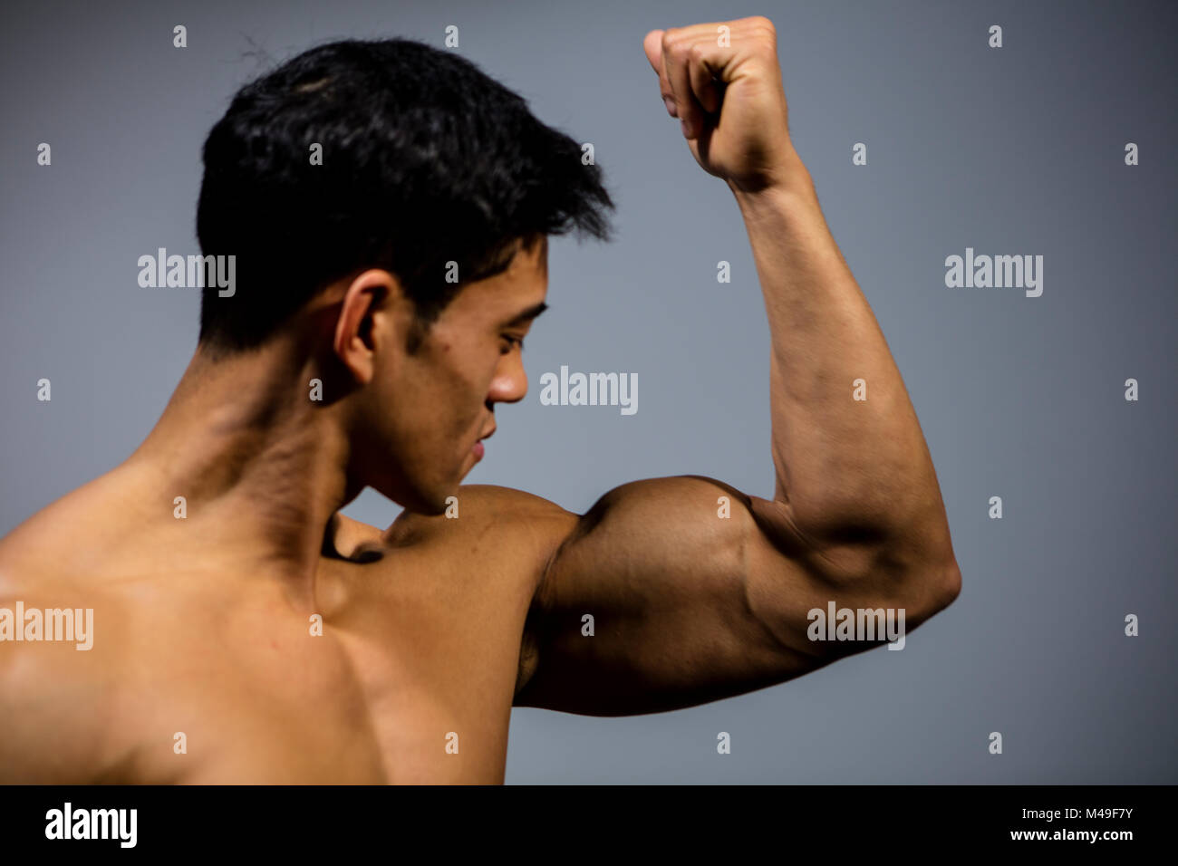 A fitness model flexes his bicep looking towards the muscle. Medium ...