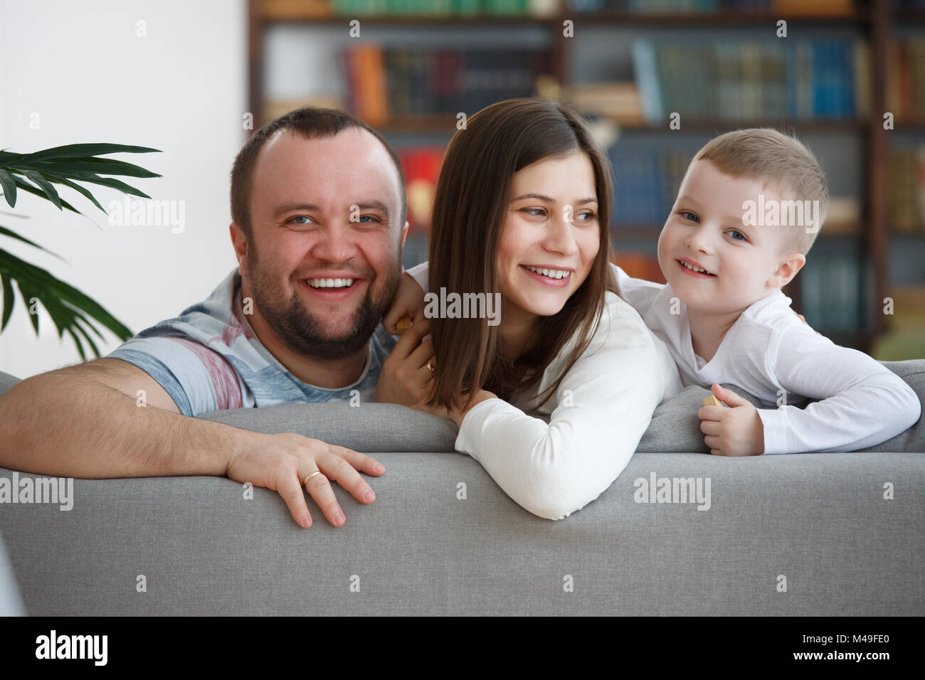 Image of smiling parents with son sitting on gray sofa Stock Photo - Alamy