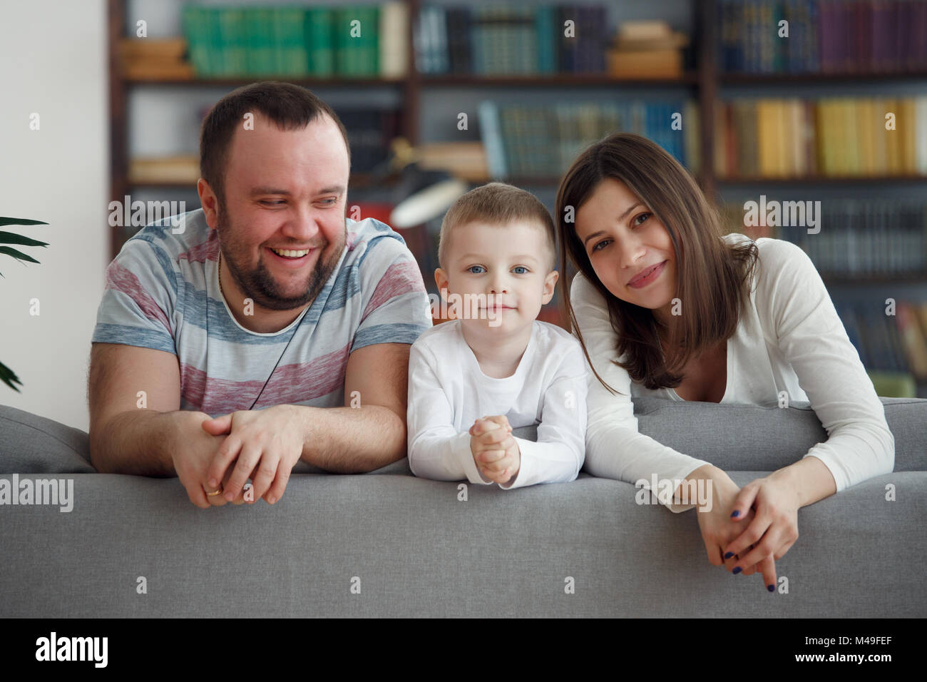 Photo of happy parents with boys on gray sofa Stock Photo - Alamy