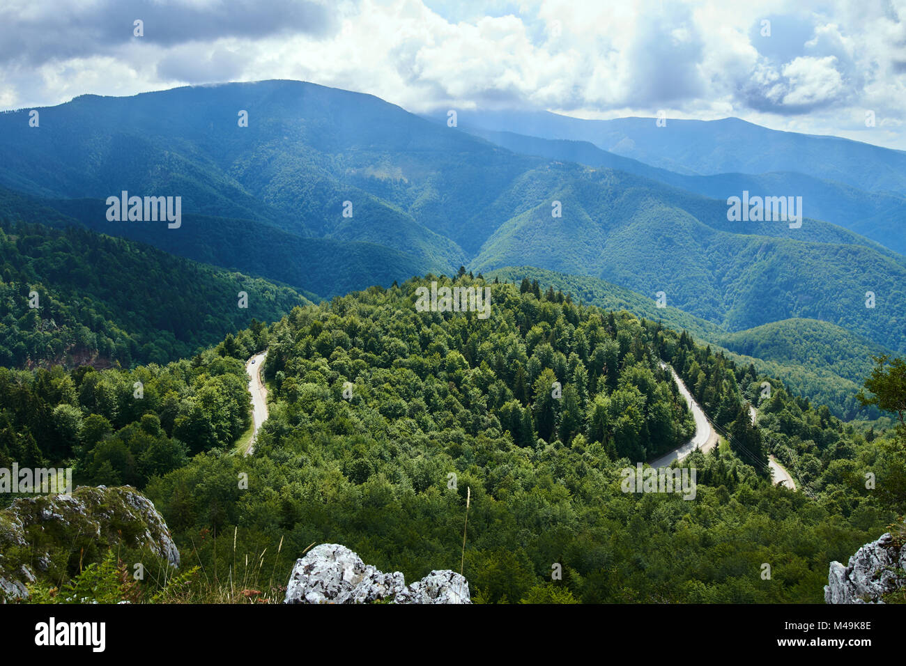 Aerial view over mountains covered in forests and a winding road Stock ...