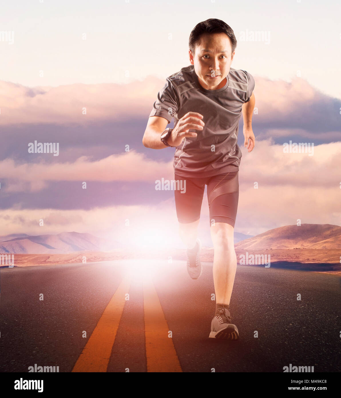 younger running man on asphalt highway against beautiful sunset sky and ...
