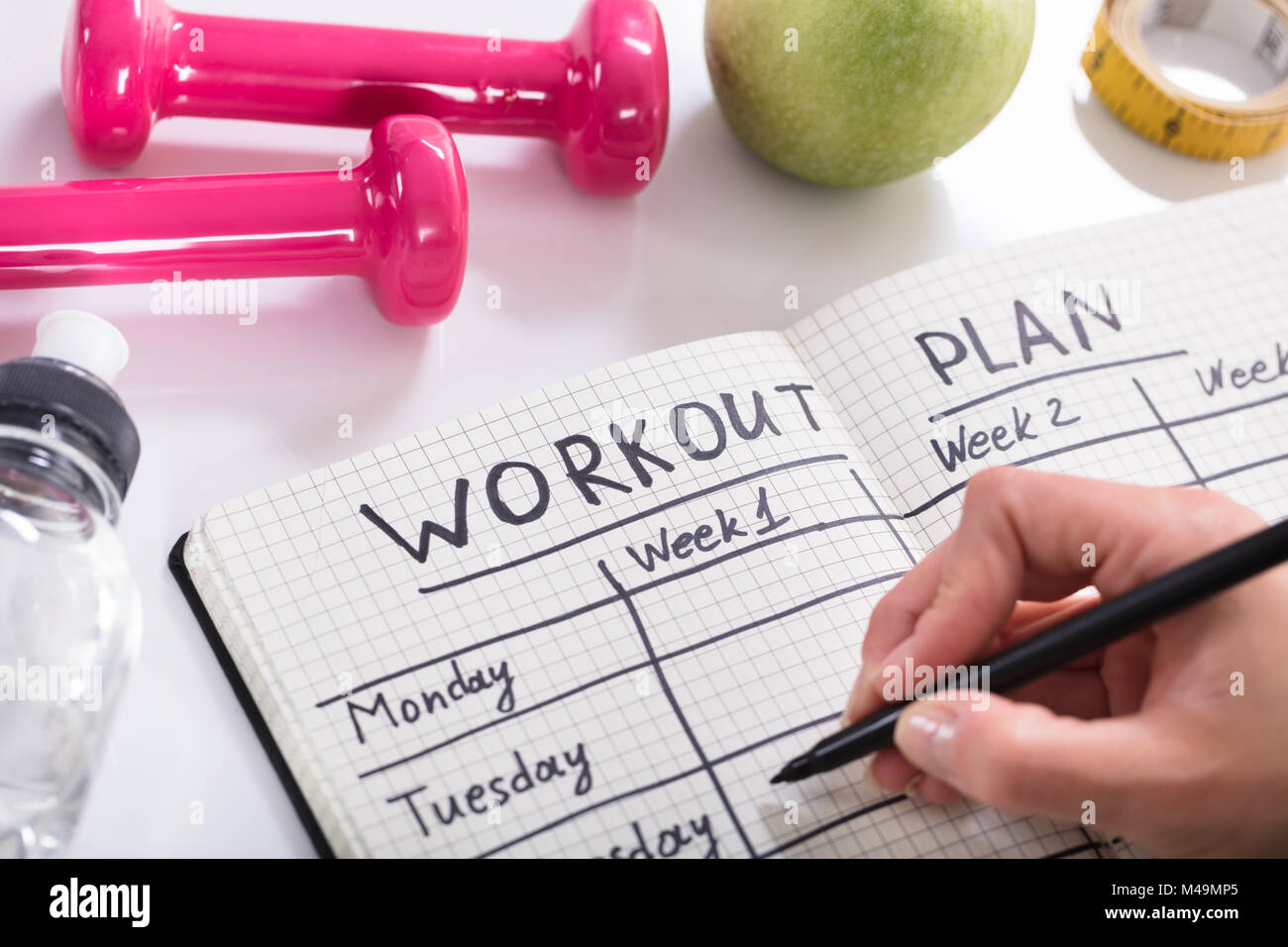 Woman Writing Workout Plan In Notebook At Wooden Desk Stock Photo - Alamy