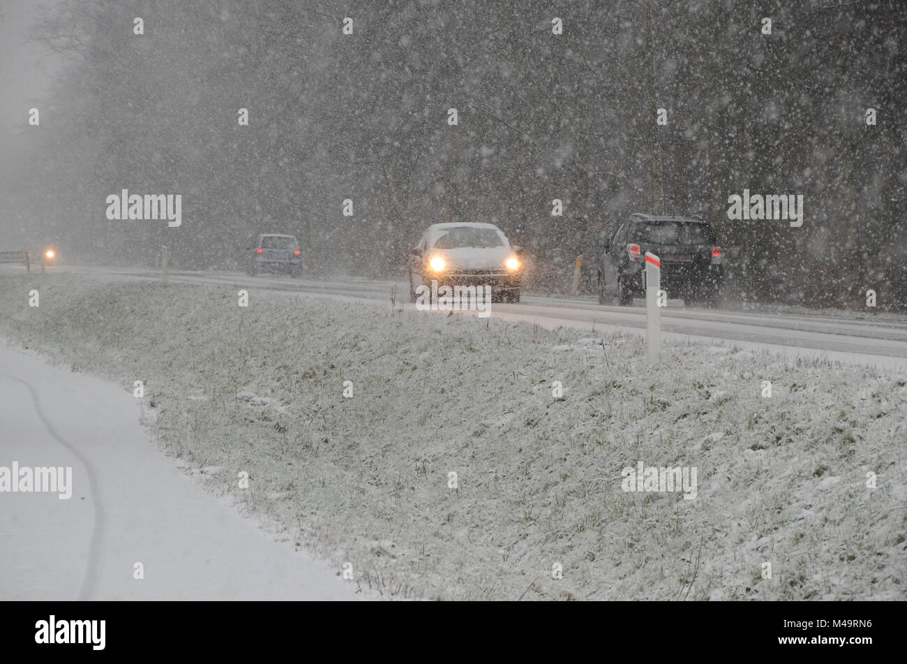 Sparse traffic moving slowly, on a road during heavy snowfall that ...