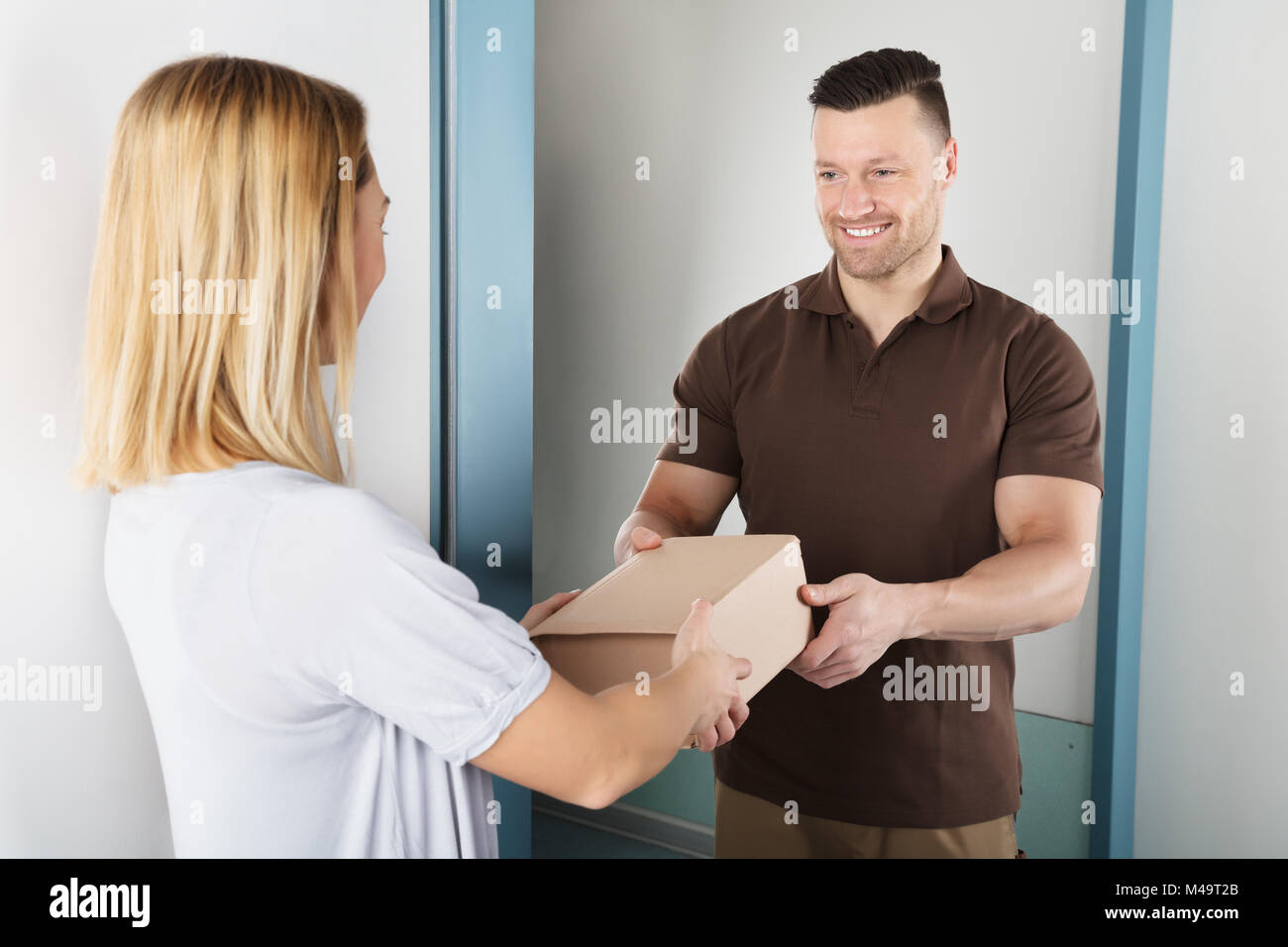 Happy Young Woman Accepting Parcel Box From Delivery Man Stock Photo ...