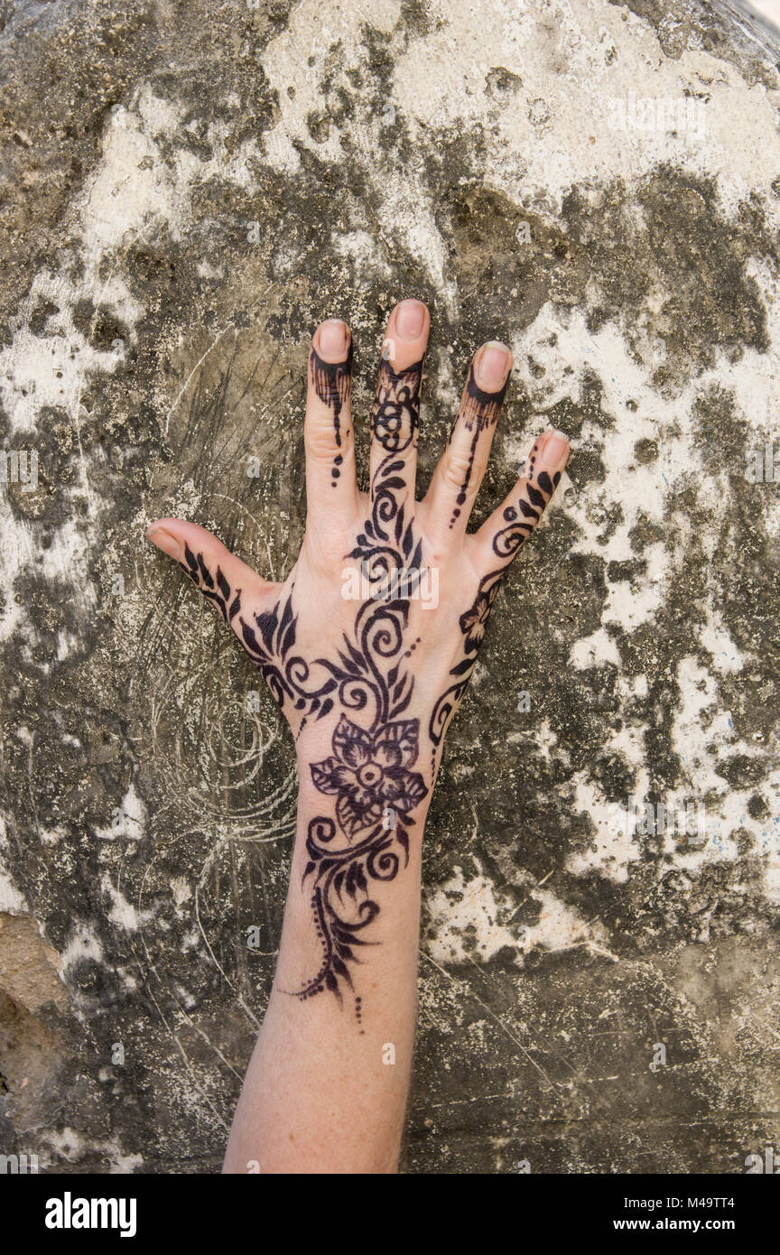 Woman's henna decorated hands against a stone wall in Stone Town ...