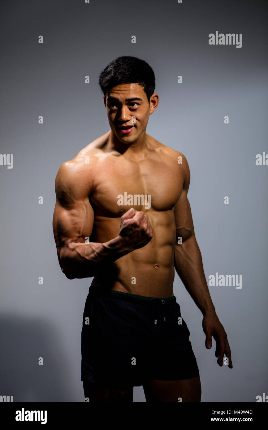 An Asian fitness model poses for the camera and smiles. Medium shot ...