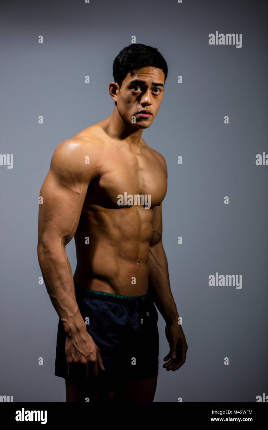 An Asian fitness model poses for the camera looking away into the ...