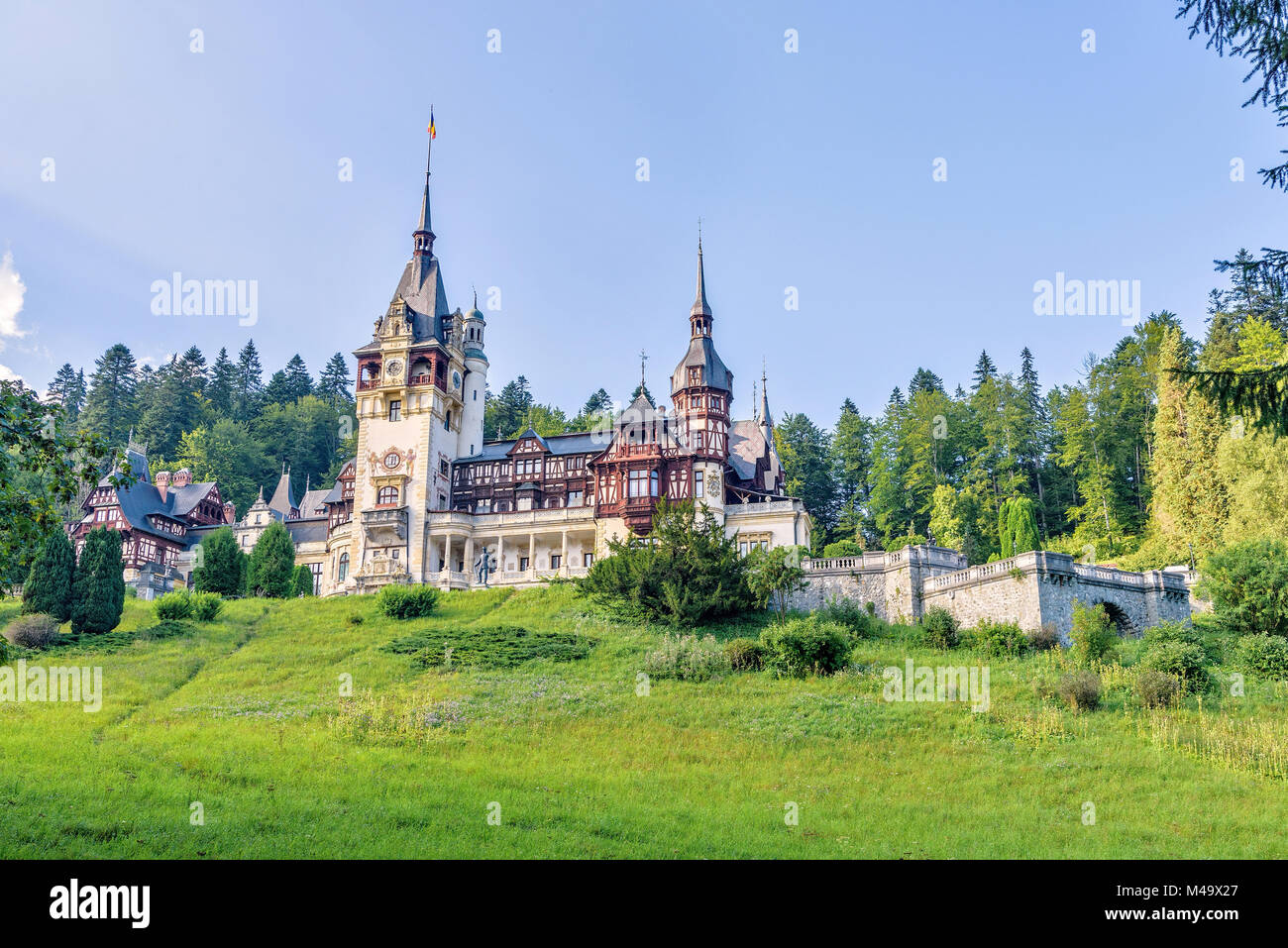 Daylight side far view to Peles castle front facade with hanging flag ...