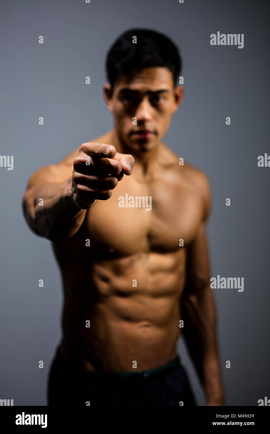 Asian fitness model pointing forward with a stern facial expression ...