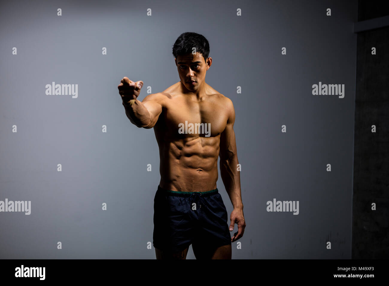 Asian fitness model pointing forward with a stern facial expression ...