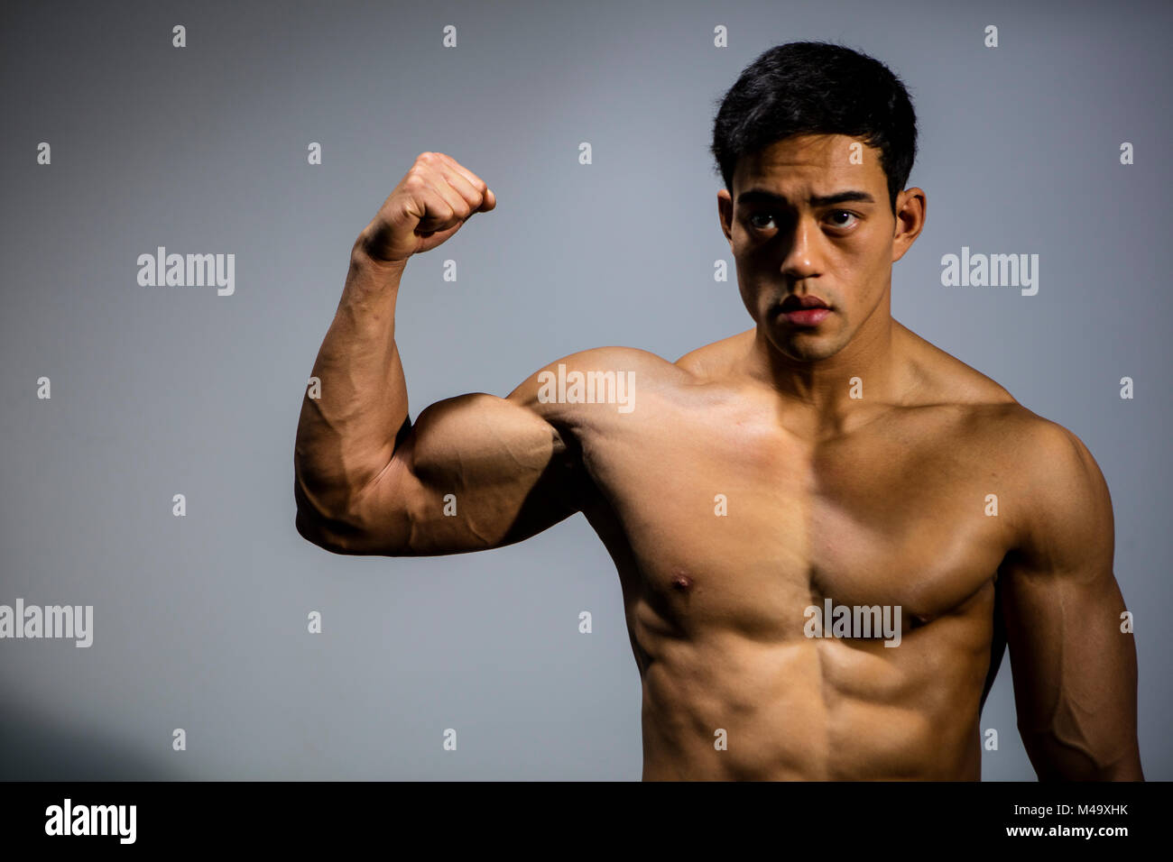 An Asian fitness model flexing his bicep muscle. Front facing Stock ...