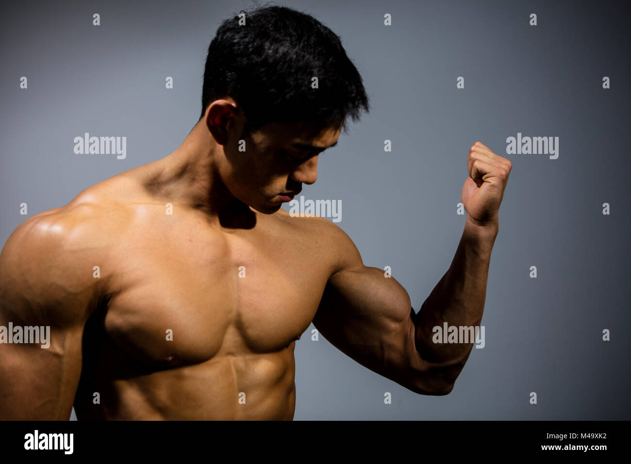 A fitness model flexes his bicep looking towards the muscle. Medium ...