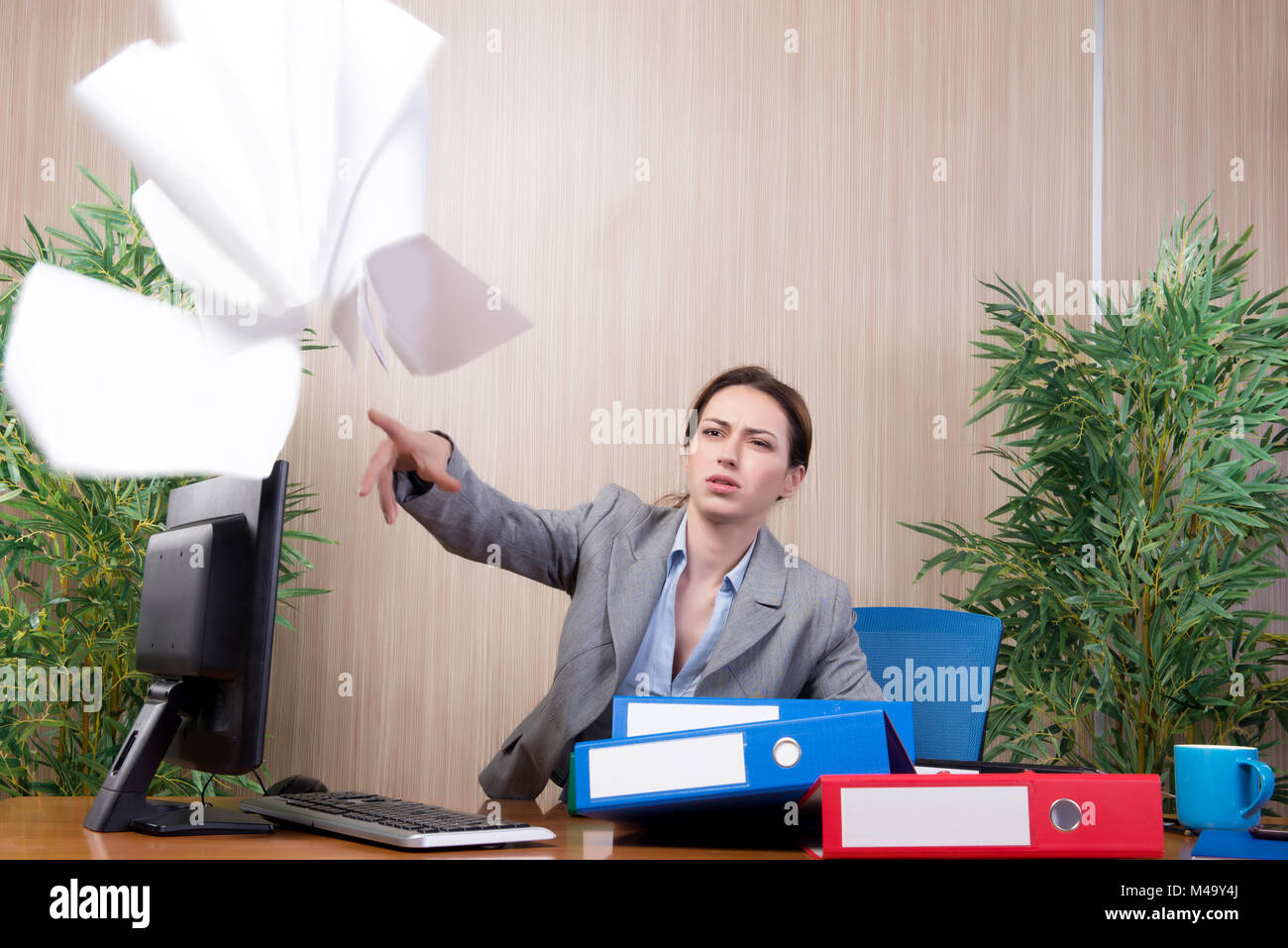 Woman under stress tossing papers in the office Stock Photo - Alamy