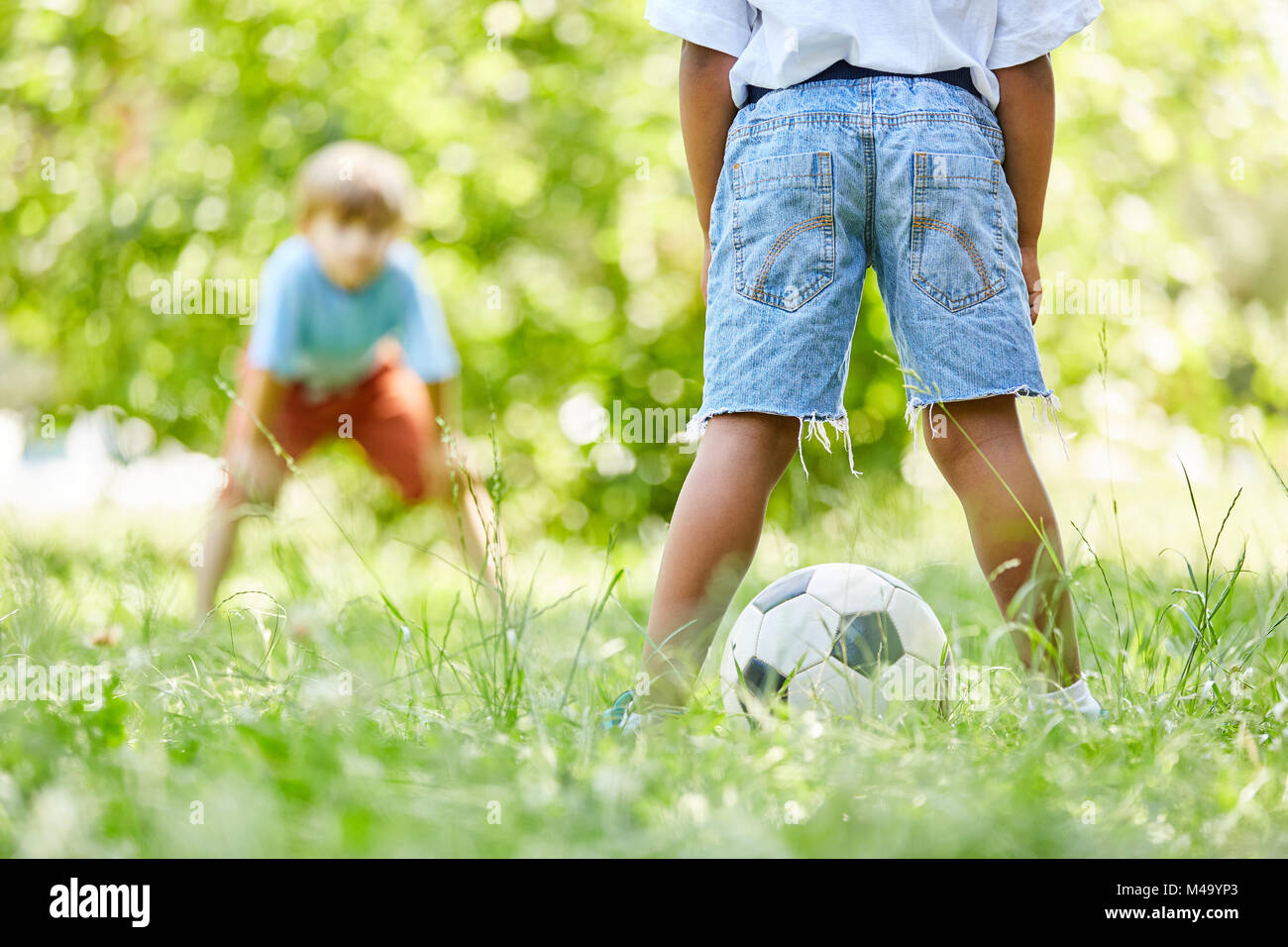 Two kids play soccer together on a meadow in summer Stock Photo - Alamy