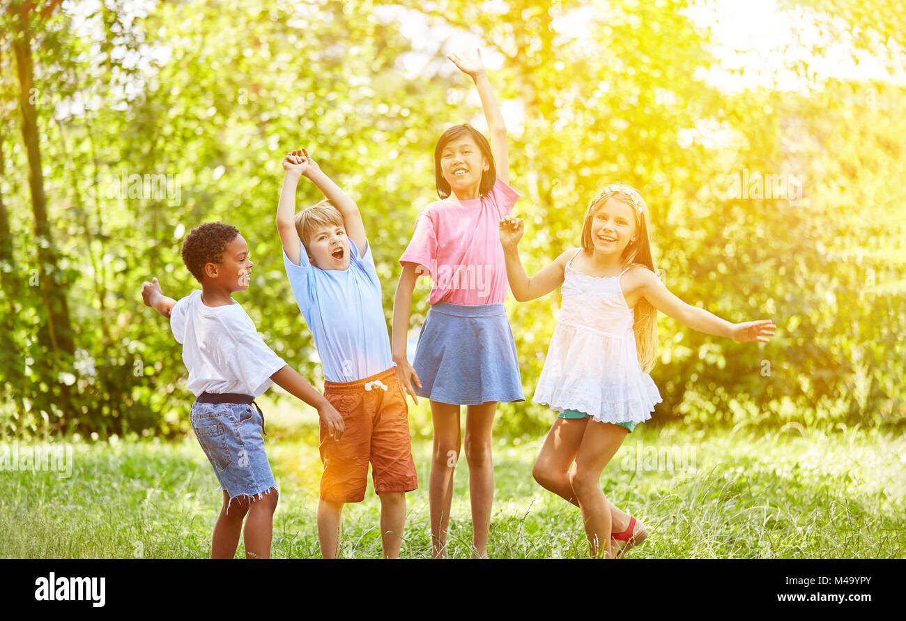 Group of kids cheering and dancing in summer in the park Stock Photo ...