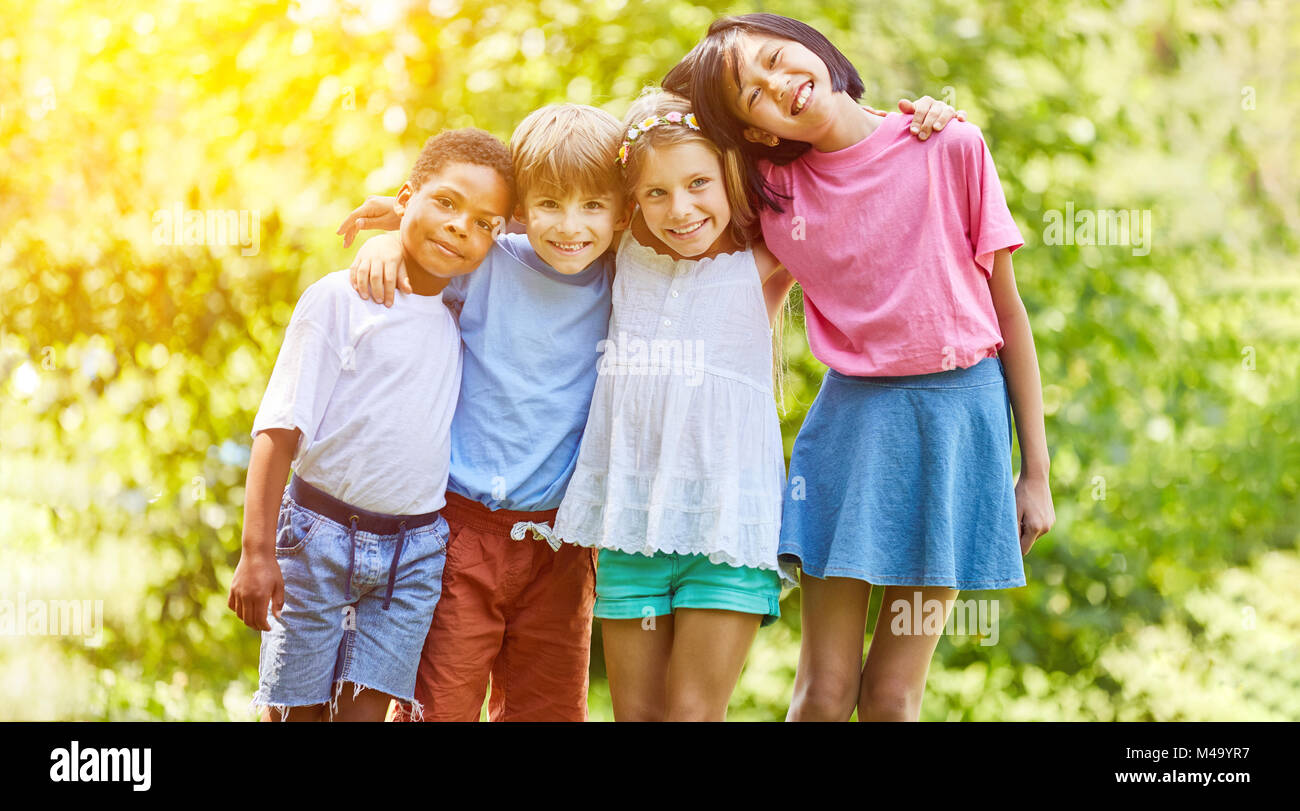 Happy multicultural group of kids hugs each other in summer Stock Photo ...