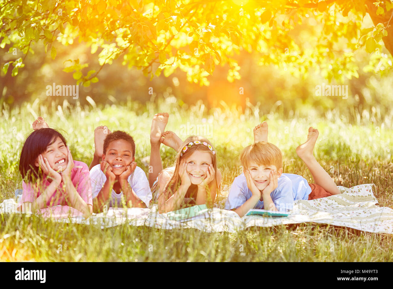 Multicultural group of children lies happily on a blanket in summer in ...