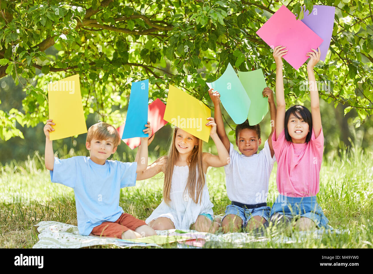 Children of creative craft group hold colorful cartons high in the park ...
