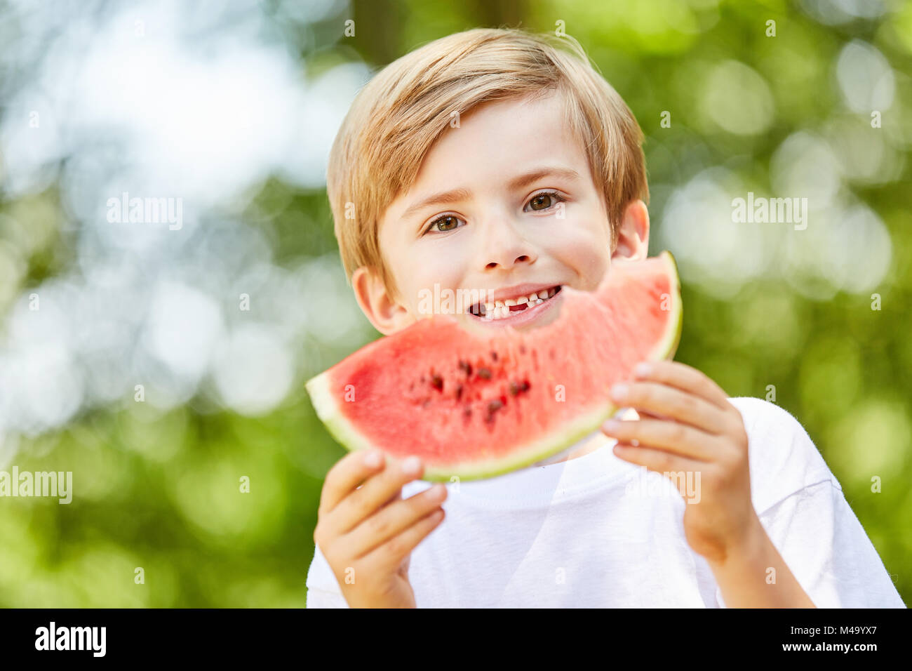 Hungry boy at a party is eating a delicious and healthy watermelon ...