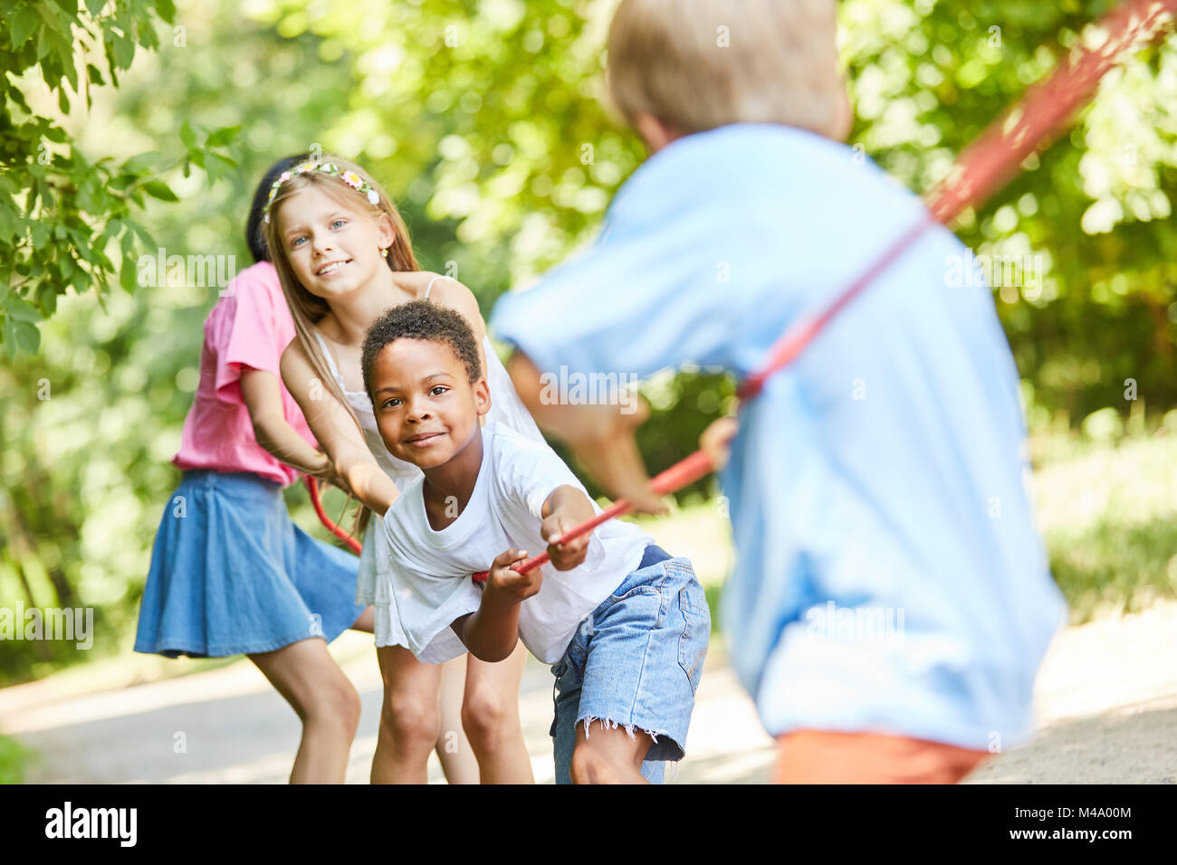Group of kids in tug-of-war competition as a strong team in nature ...