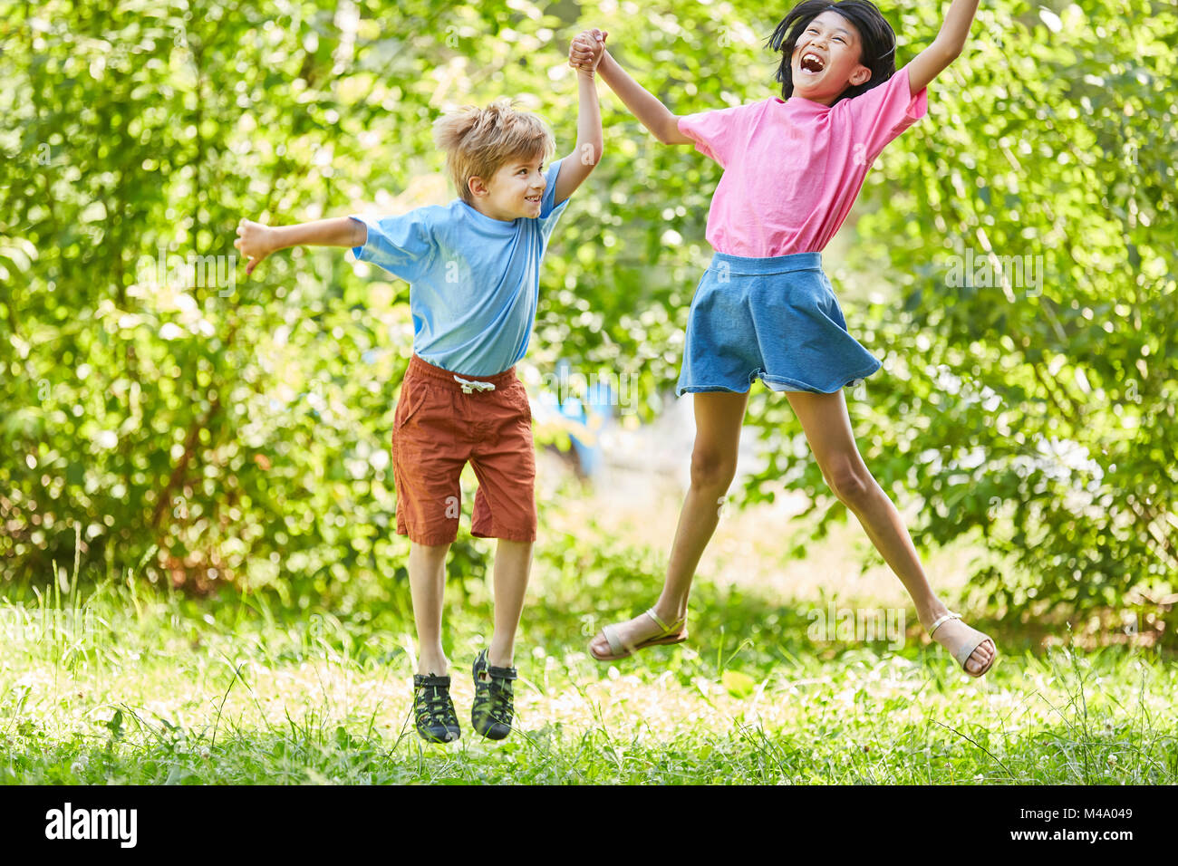 Boy and girl cheer together and jump into the air, laughing Stock Photo ...