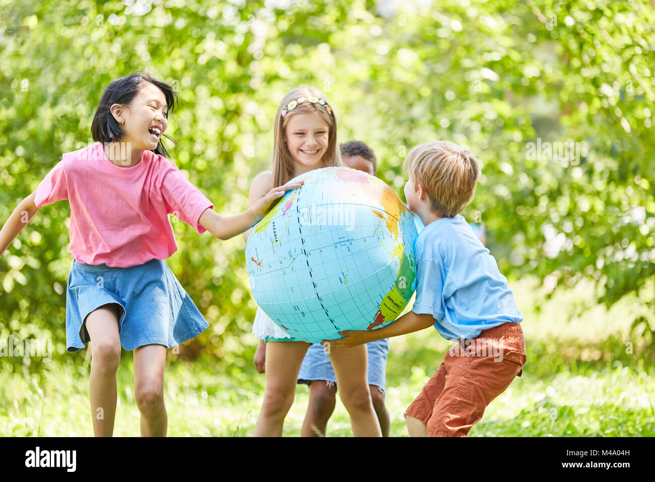 Multicultural group of kids plays in summer with globe ball Stock Photo ...