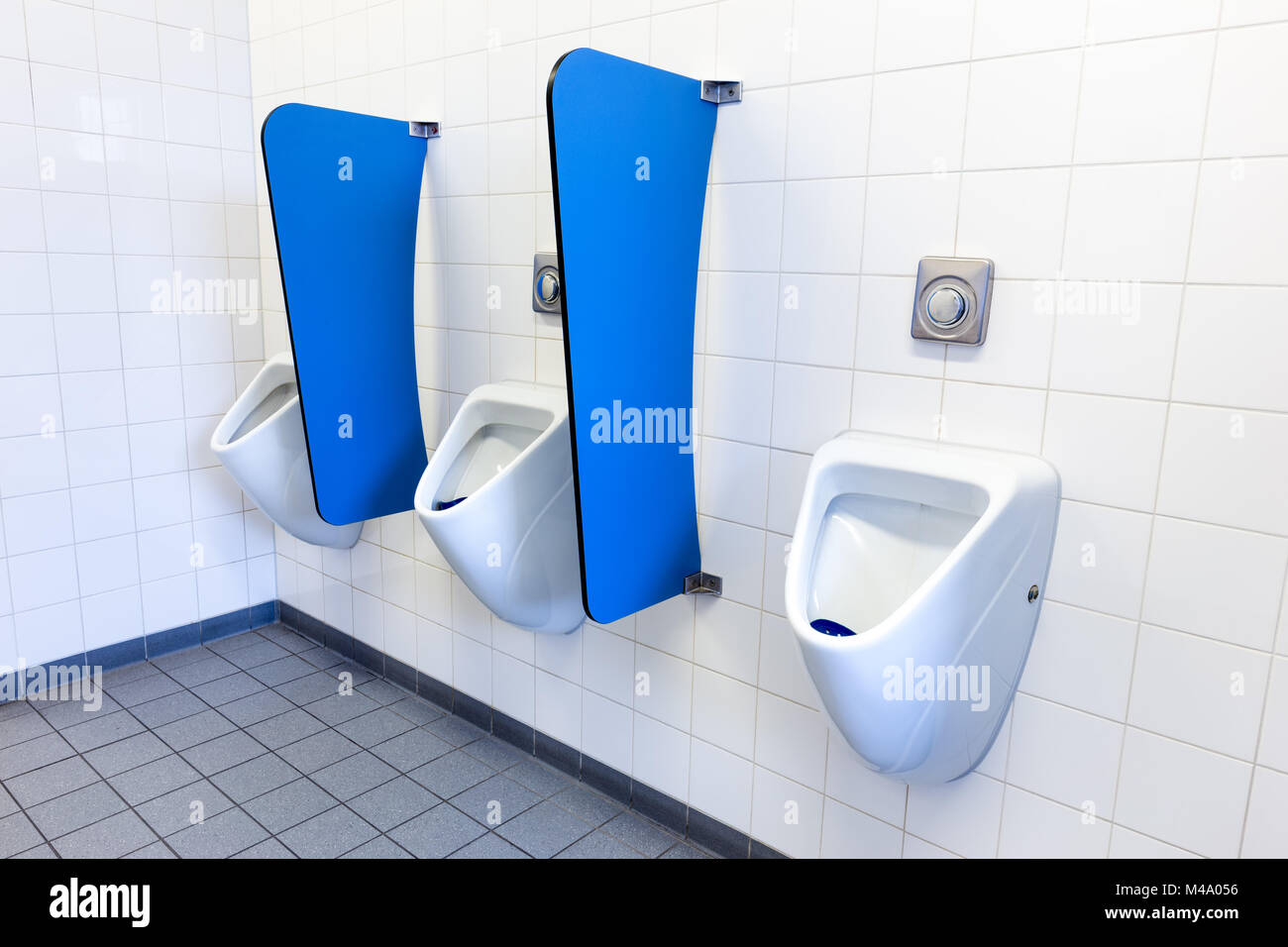 Men's urinals on white wall with blue partitions Stock Photo - Alamy
