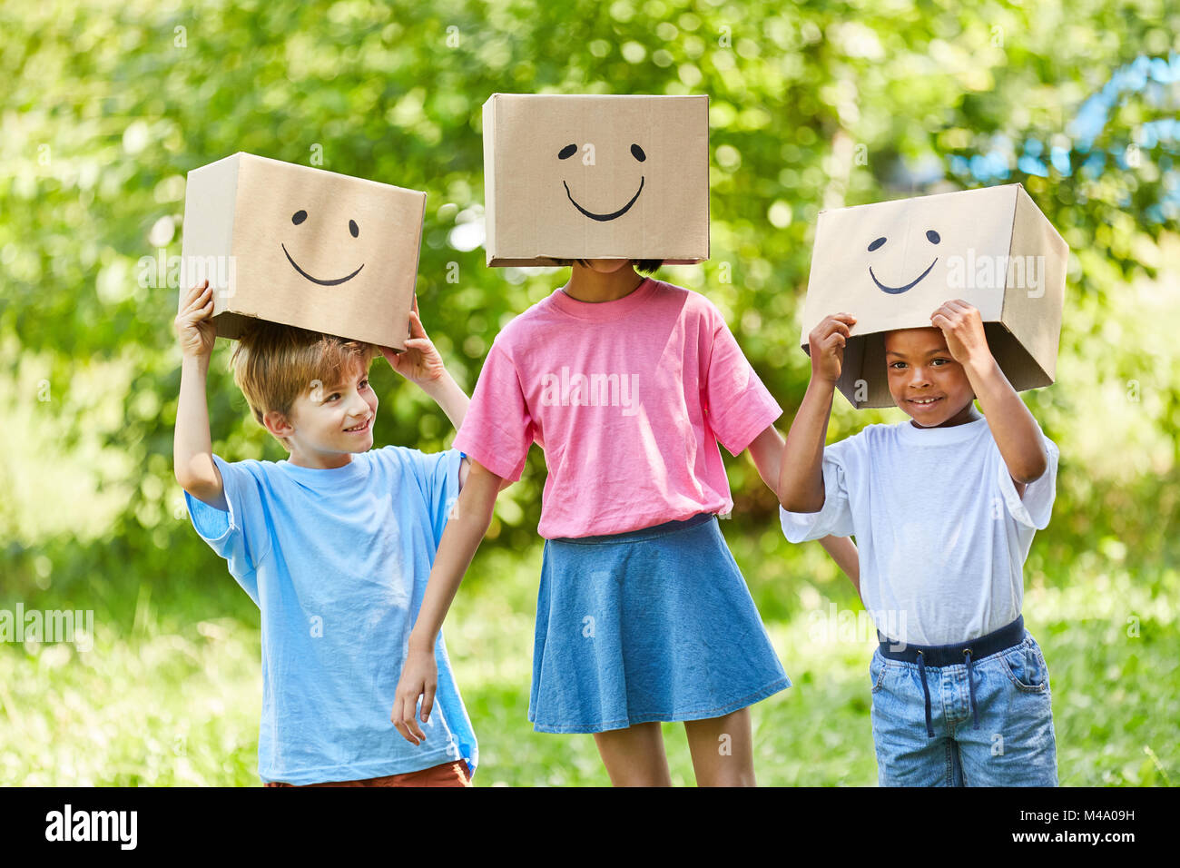 Three children play with fantasy with funny painted cardboard boxes in ...