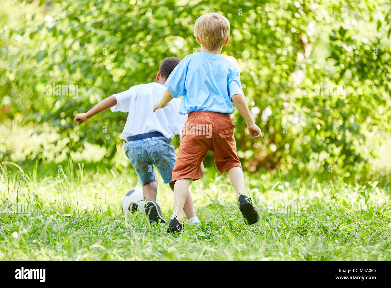 Two athletic boys playing football follow the ball Stock Photo - Alamy