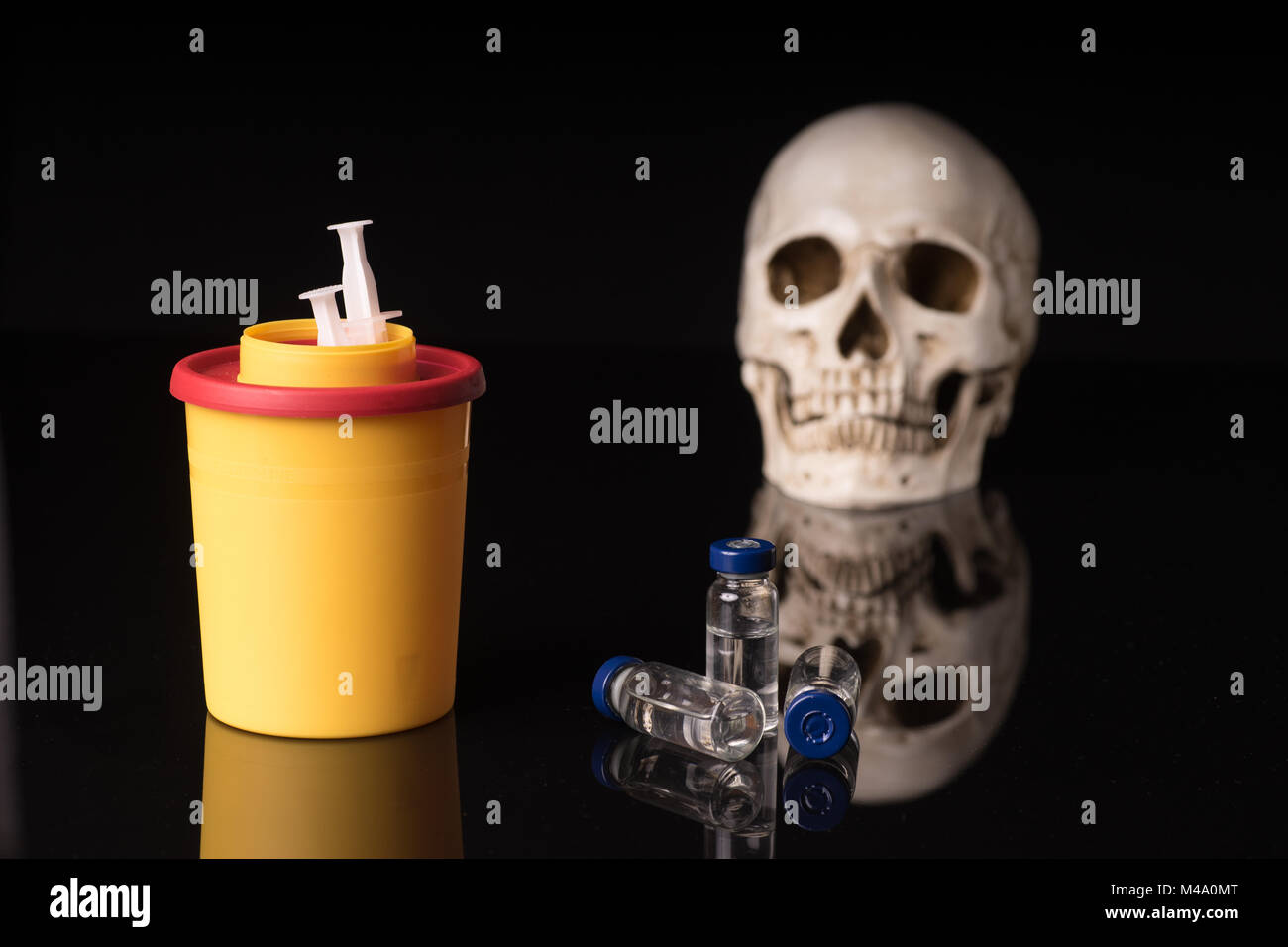 Skull, syringe and yellow waste container, isolated on black with ...