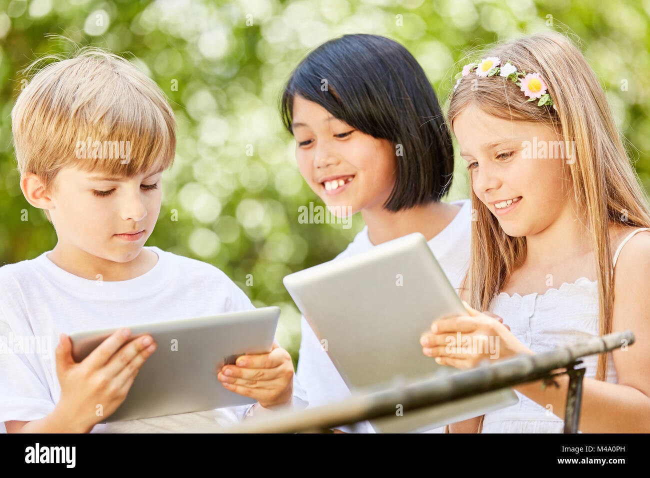 Three kids with tablet computer learn together in computer course in ...