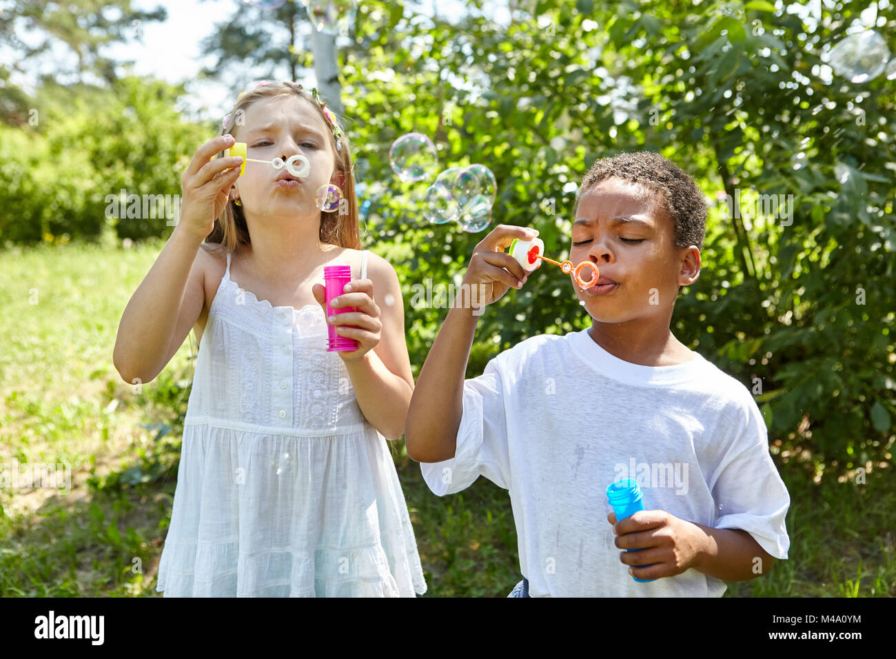 Girl and African boy as a friend are blowing bubbles together Stock ...