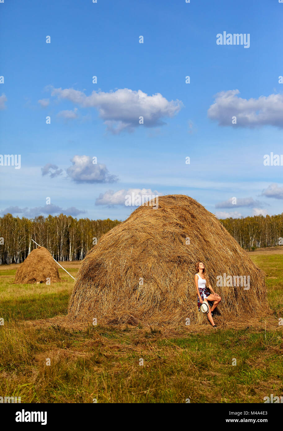 Young blonde country girl in hat near haystack Stock Photo - Alamy