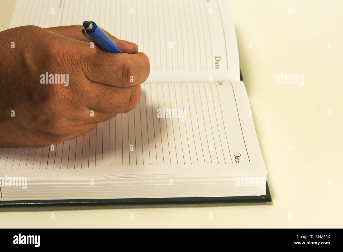 Man's hand holding a pen to write in the diary Stock Photo - Alamy
