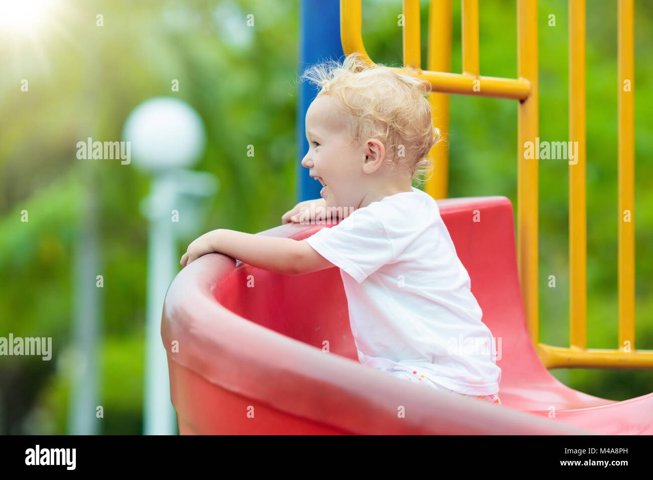 Kids climbing and sliding on outdoor playground. Children play in sunny ...