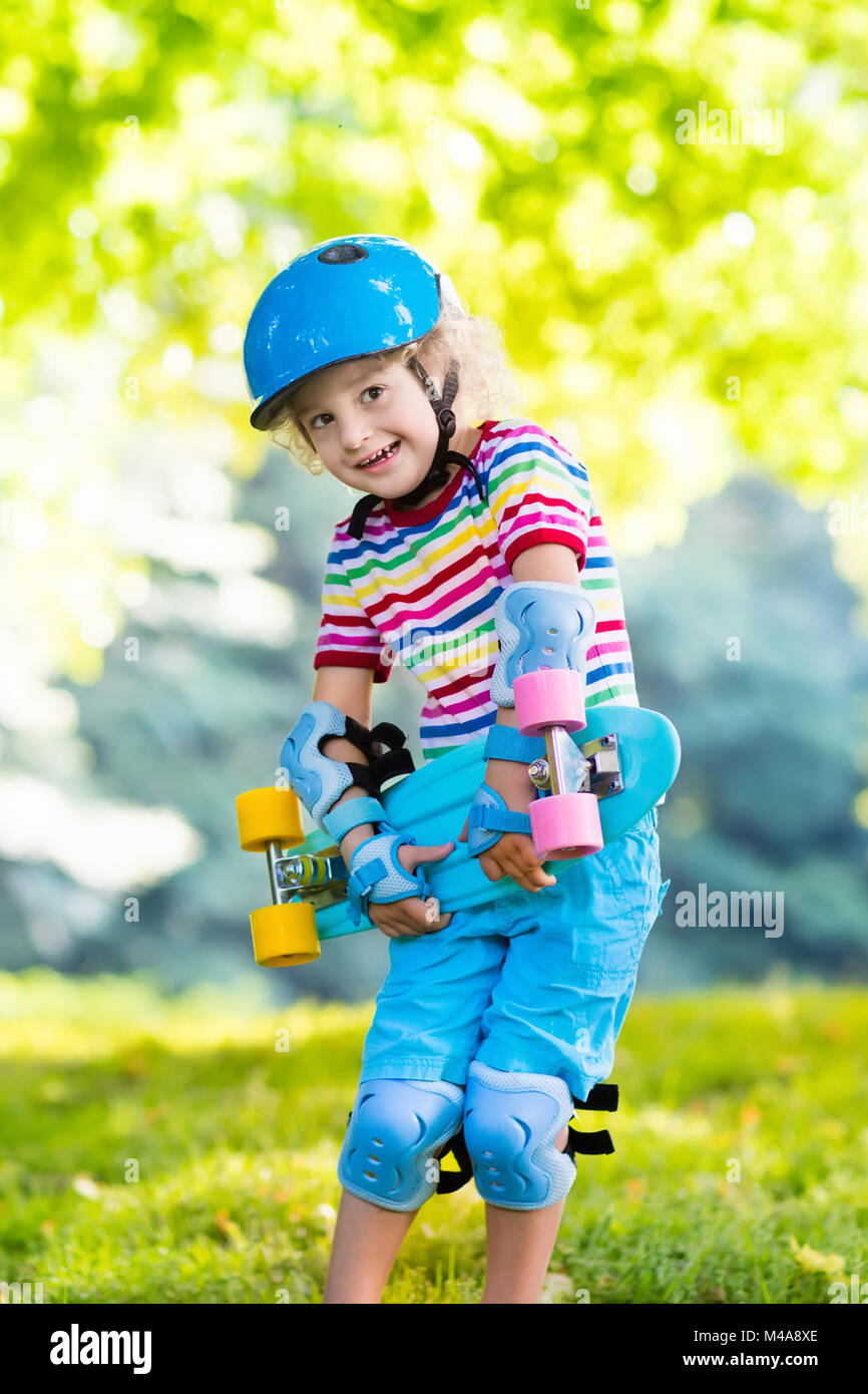 Child riding skateboard in summer park. Little boy learning to ride ...