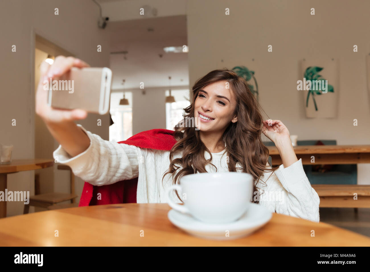 Portrait of an attractive woman taking a selfie while sitting at the ...